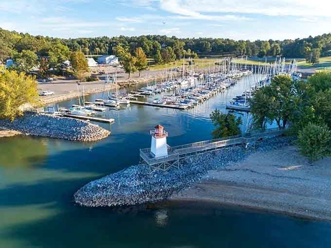 That charming lighthouse guards the marina entrance where sailboats rest peacefully between adventures on the water.