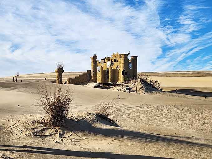 Sand dunes meet abandoned structures in this surreal coastal landscape that looks straight out of a movie set.