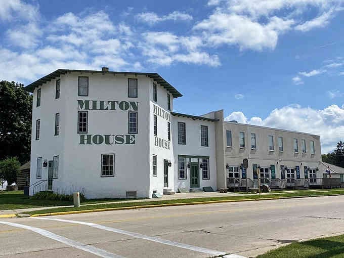 The Milton House stands proud under blue skies, its historic walls stretching toward modern additions with quiet dignity.