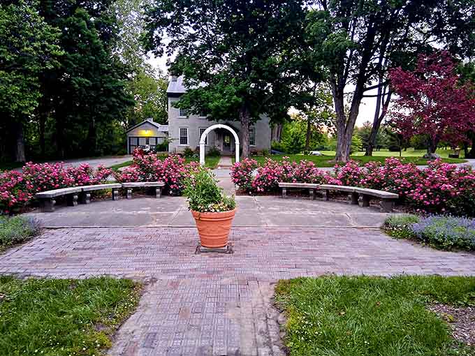 Pink roses frame a white archway leading to what looks like a scene from "The Secret Garden" come alive.