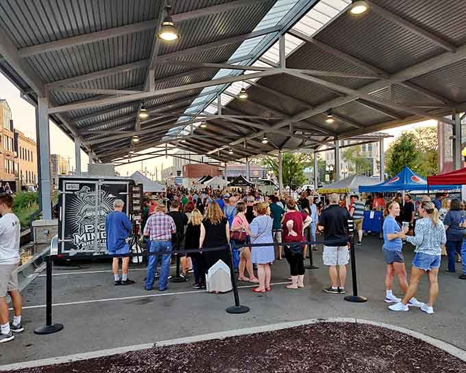 The covered pavilion shelters shoppers and sellers alike, creating a bustling marketplace that feels like a neighborhood gathering.