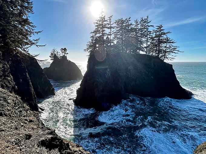 Sunlight breaks through coastal mist, illuminating rock formations that stand guard along this wild, untamed shoreline like sentinels.