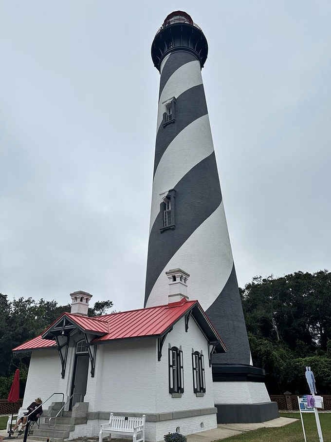 The keeper's cottage with its cheerful red roof sits faithfully beside this towering coastal sentinel watching the waves.