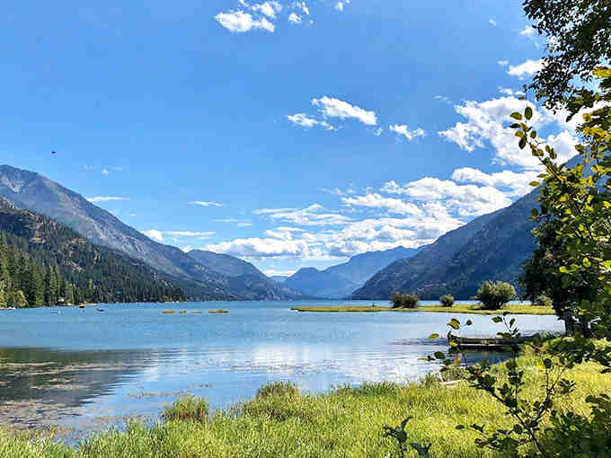 Perfect blue skies frame this alpine lake where mountains stand guard like ancient sentinels over paradise.