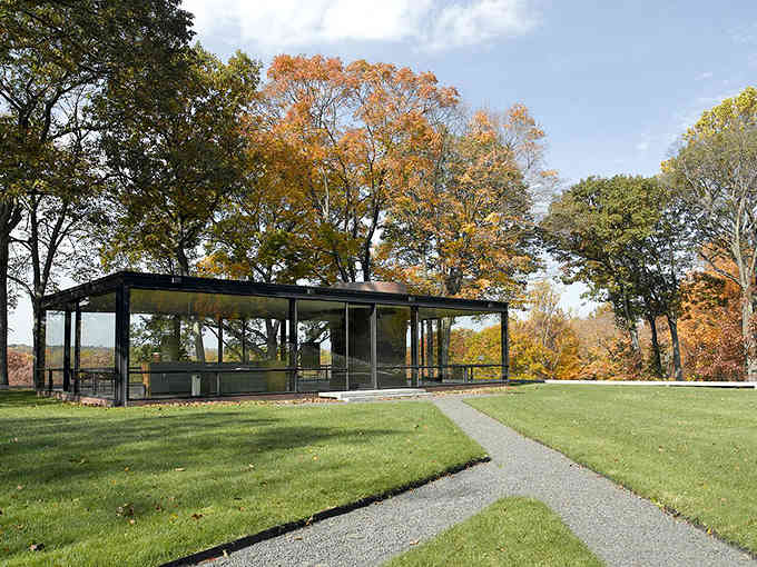 Fall foliage frames this transparent masterpiece where indoor and outdoor living blend like a perfect cocktail.