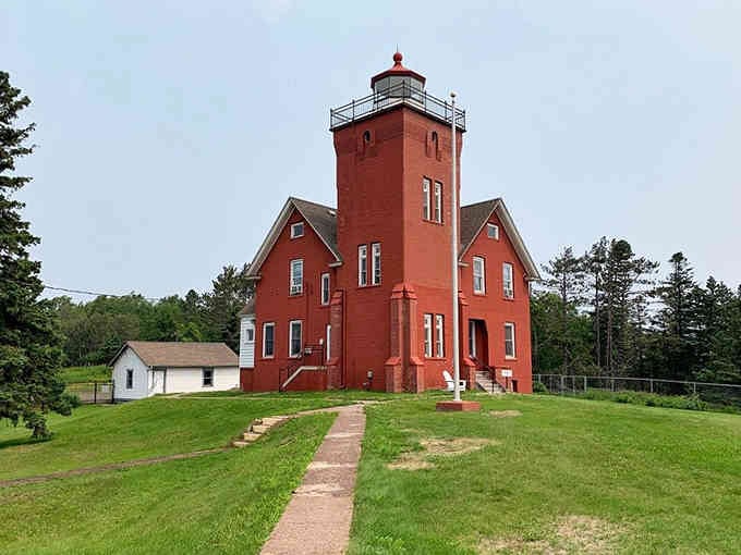 The fog signal building stands ready beside the main tower, white against red like a nautical exclamation point.