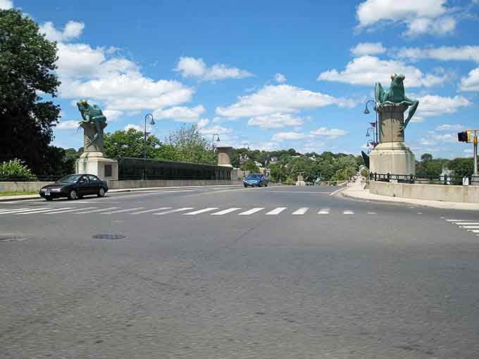 A grand bridge flanked by majestic statues stands guard over Willimantic's historic crossing—where small-town charm meets monumental ambition.