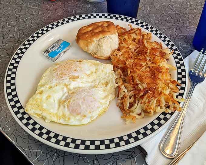 Hash browns, eggs, and a biscuit on a checkered plate: breakfast that understands the assignment perfectly.