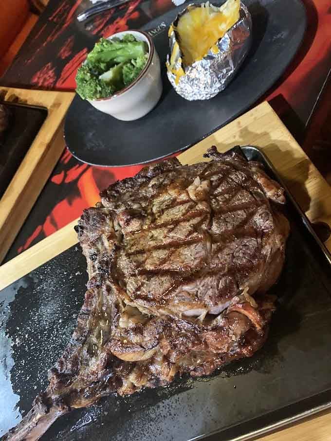 Behold the cowboy steak in all its bone-in glory, served on a wooden board like edible architecture.