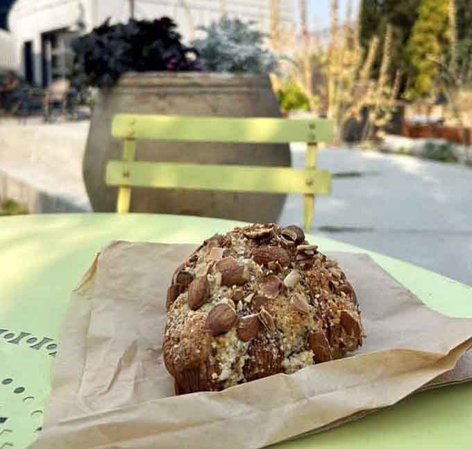 This almond croissant sitting on that bright green bench is living its best pastry life.