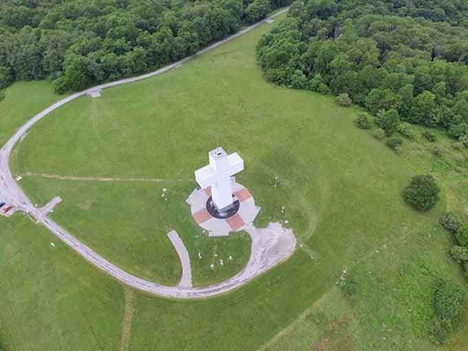 From above, the cross sits like a jewel atop its emerald throne, surrounded by endless forest canopy.