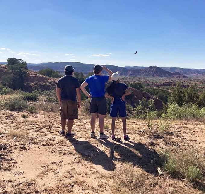 Three explorers contemplate the canyon's majesty, probably wondering if they packed enough snacks for this adventure.