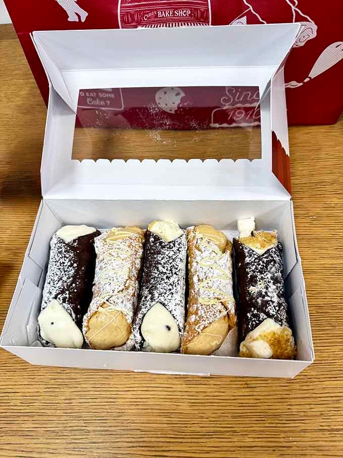 Fresh-filled cannoli lined up like edible soldiers, their chocolate-dipped ends standing at attention, ready to make your taste buds salute.