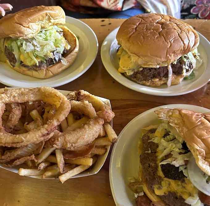 Three burgers and a mountain of rings proving that sometimes excess is exactly what the doctor ordered, metaphorically speaking.