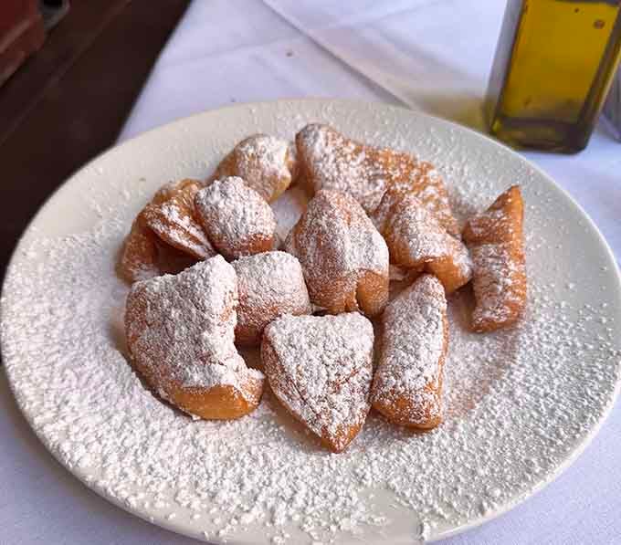 Golden pillows of fried dough dusted with powdered sugar arrive free, proving that good things really do come to those who sit.