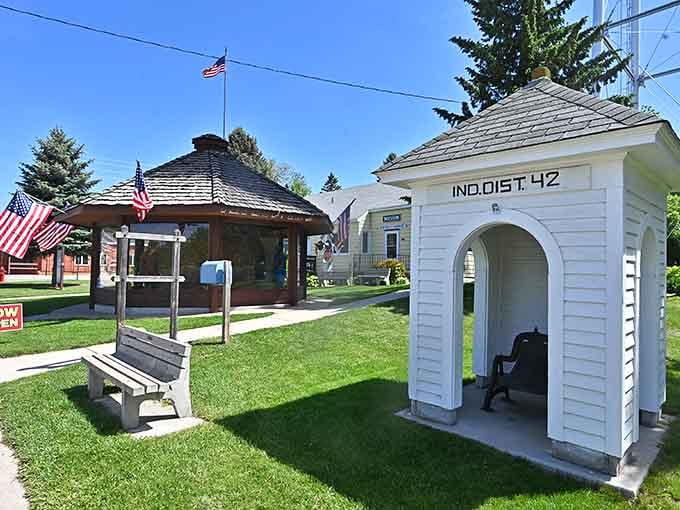 That charming white outhouse adds small-town character, because even roadside attractions need proper facilities and patriotic flair.