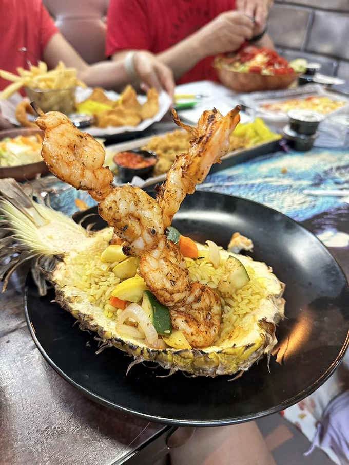 Shrimp served in a hollowed pineapple with fried rice, proving that tropical presentation never went extinct after all.