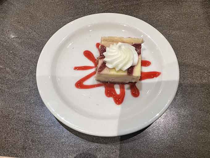 Raspberry cheesecake drizzled with sauce proves that sometimes simple presentation lets the flavors do all the talking.