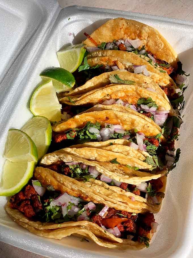 Six perfect tacos lined up like edible soldiers, each one packed with flavor and topped with fresh cilantro and onions.