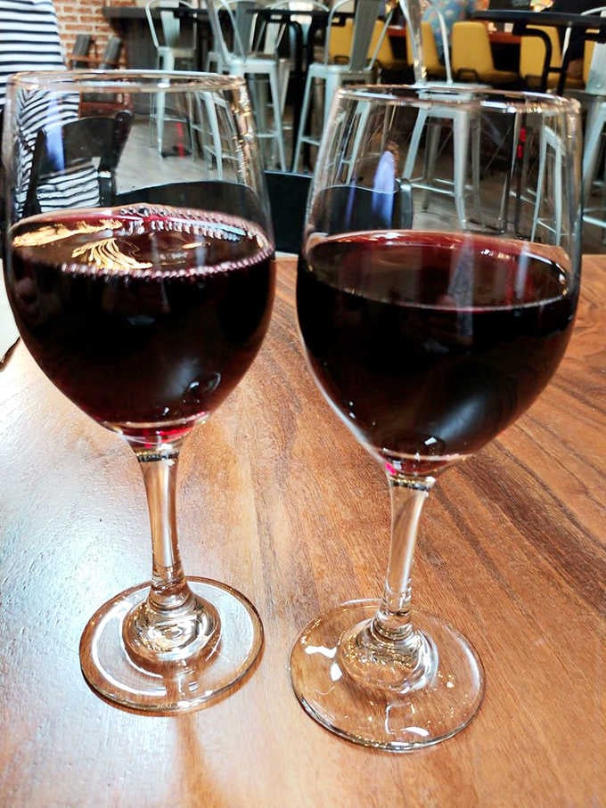 Two glasses of red wine on a wooden table, the universal symbol of civilized conversation about to happen.