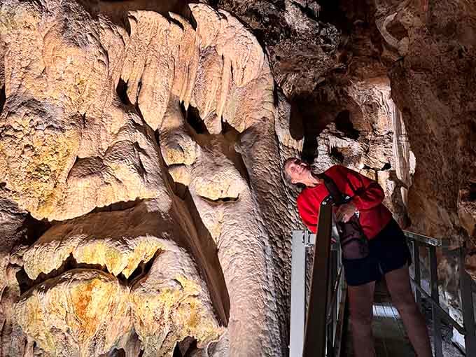 Standing beneath rippling stalactites that hang like nature's elaborate curtains, this explorer appreciates slow-motion artistry at its finest.
