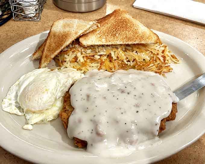 Country fried steak drowning in peppery gravy with hash browns and eggs: breakfast's answer to winning the lottery, minus the taxes.