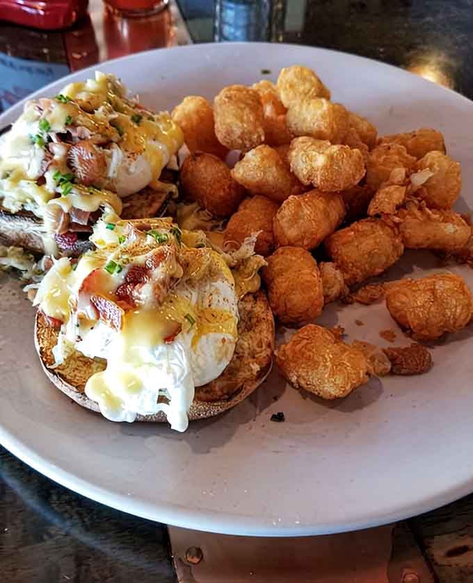 Behold the Crab Cake Benedict in all its golden-yolked glory, surrounded by crispy tater tots that deserve their own fan club.