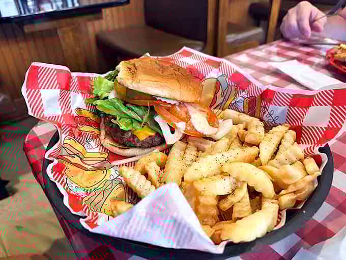 That burger towers like a delicious skyscraper, loaded with fresh toppings and served alongside perfectly seasoned fries.