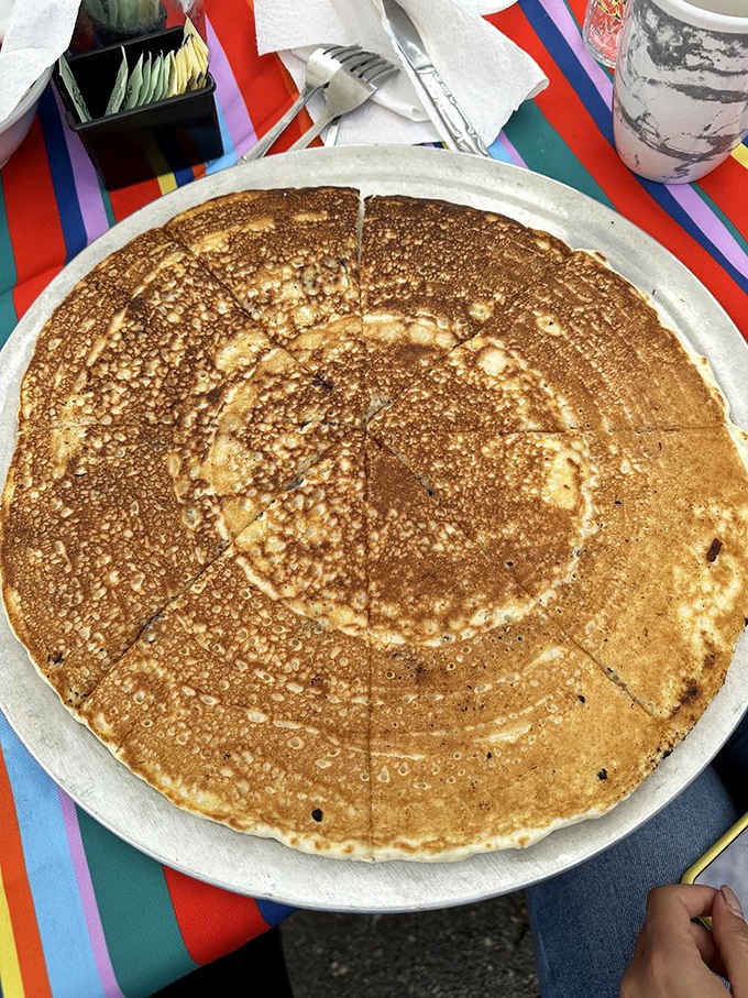 Behold: a pancake so massive it requires a pizza pan because regular plates simply waved the white flag.