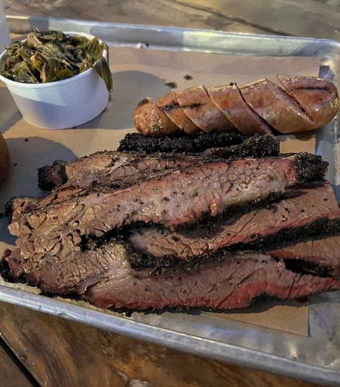 Brisket with that perfect smoke ring, sliced sausage, and collard greens, this is what barbecue dreams look like.