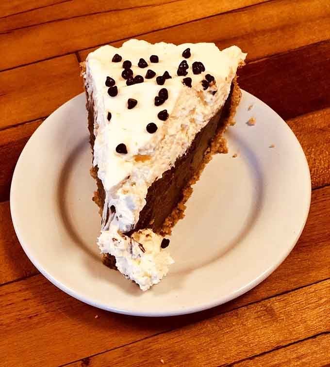 Chocolate cream pie crowned with whipped peaks and chocolate chips, defying both gravity and your willpower simultaneously.
