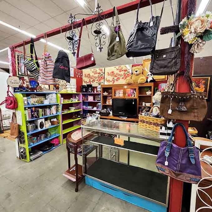 Purses hanging overhead like fashionable stalactites, because apparently gravity is just a suggestion in antique malls.
