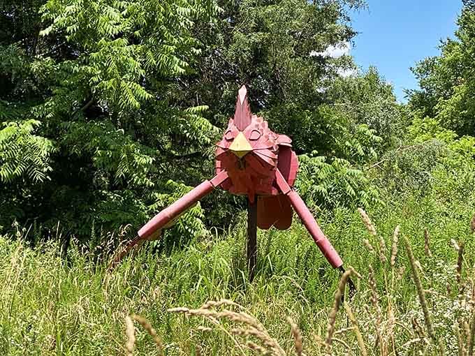 A whimsical pink bird sculpture perches in the tall grass, looking like Big Bird's artsy cousin visiting from SoHo.