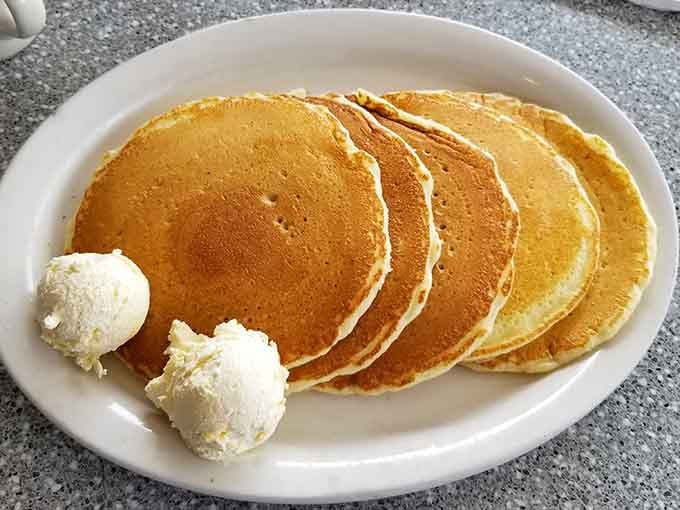 Five golden discs of pure morning joy, topped with butter that's already surrendering to their warmth and fluffy perfection.