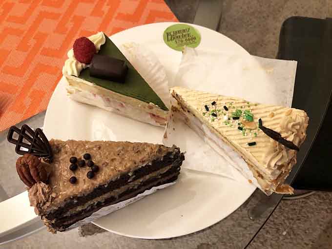 Three slices of pure temptation: chocolate, pistachio, and fruit tarts that belong in a pastry museum.