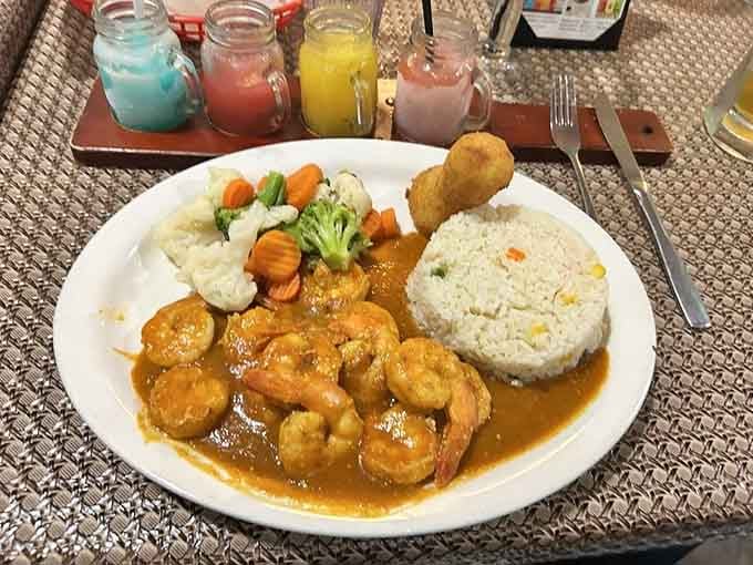 Plump shrimp swimming in golden sauce alongside perfectly molded rice, this plate could make a food photographer weep with joy.