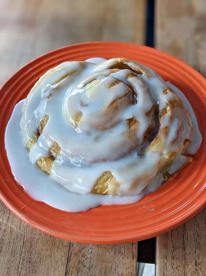 Behold the cinnamon roll that launched a thousand return trips, glistening with frosting like morning dew on perfection.