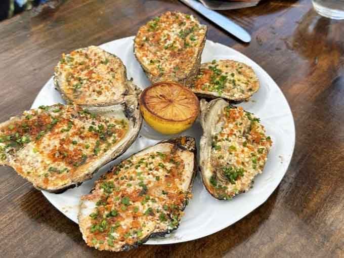 These grilled oysters arrive at your table like little treasures from the sea, topped with golden breadcrumbs and pure joy.