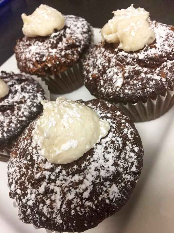 Chocolate cupcakes dusted with powdered sugar and crowned with cream &ndash; these aren't just desserts, they're tiny edible celebrations.