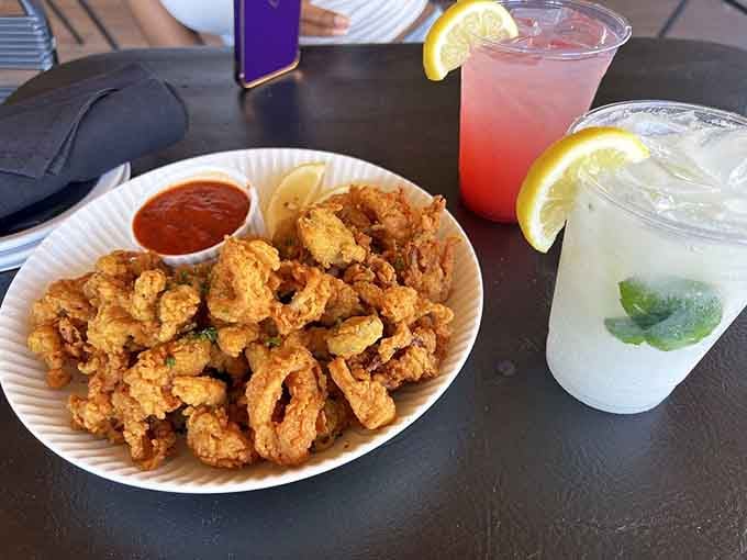 Golden-fried calamari with lemon wedges and refreshing cocktails, the perfect trio for waterside dining bliss.