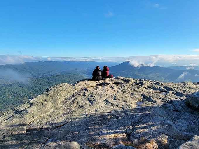 Two hikers share a quiet moment at sunrise, because some views are too good to experience alone.