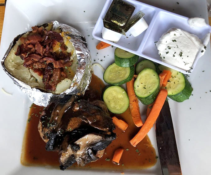 A perfectly plated meal featuring tender meat, fresh vegetables, and a loaded baked potato that means business.