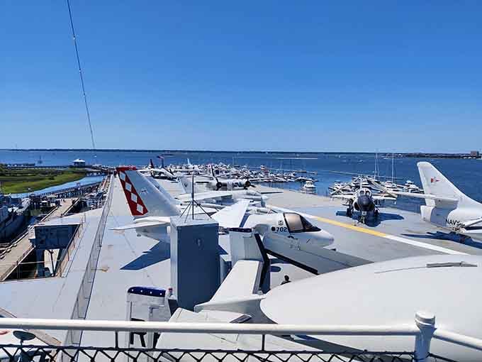 The flight deck stretches toward Charleston Harbor like a massive steel runway, aircraft frozen mid-mission against Carolina blue skies.