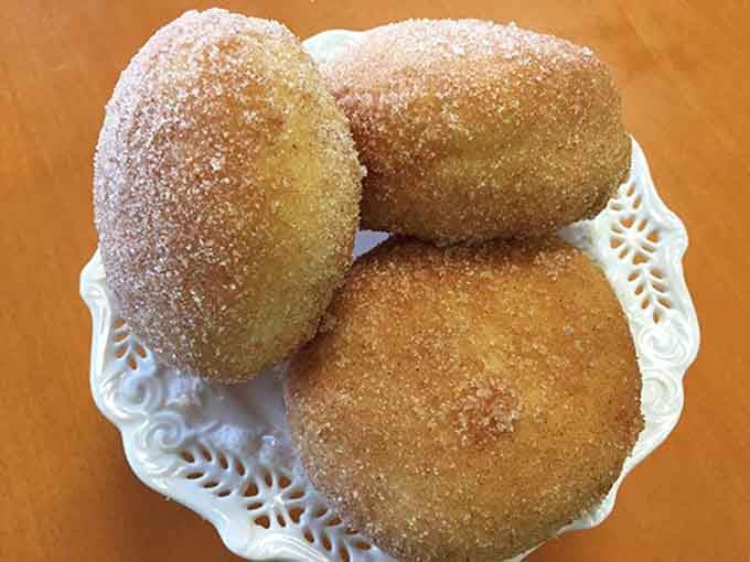 Golden cinnamon sugar donuts sparkling like edible treasure, warm and impossibly tempting on that delicate plate.