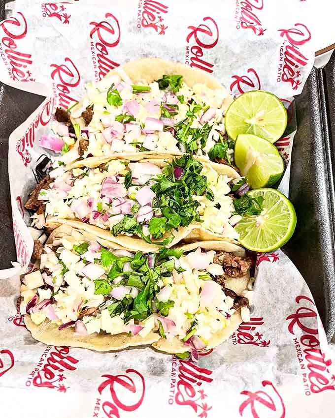 Street tacos piled high with carne asada, onions, cilantro, and lime wedges ready for action and flavor.