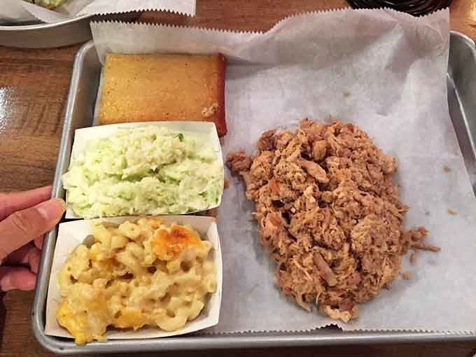Behold the holy trinity: tender chopped pork, creamy mac and cheese, and golden cornbread on a simple tray.