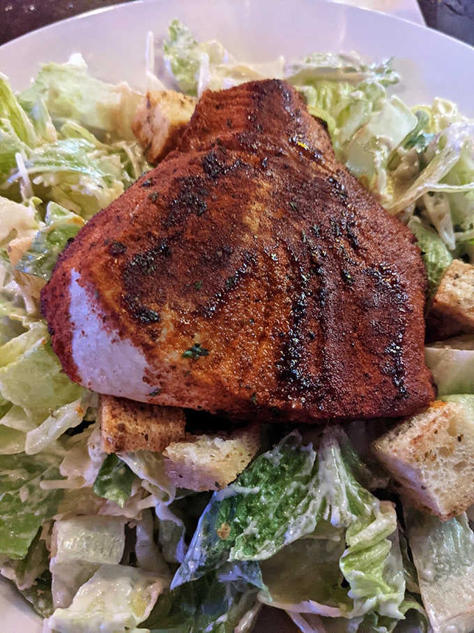 Blackened tuna steak perched on Caesar salad like it owns the place, because honestly, it does.