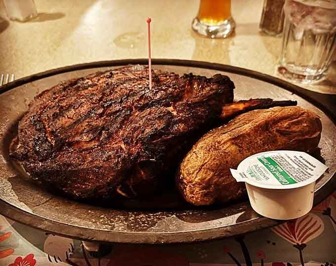 Behold the ribeye in all its glory, complete with a baked potato that's practically begging for butter and sour cream.