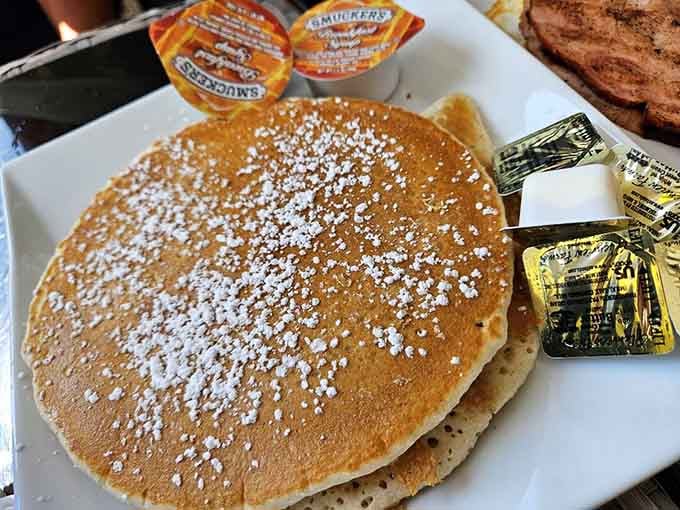 Fluffy pancakes dusted with powdered sugar like fresh snow on a delicious, edible mountain you're about to conquer.