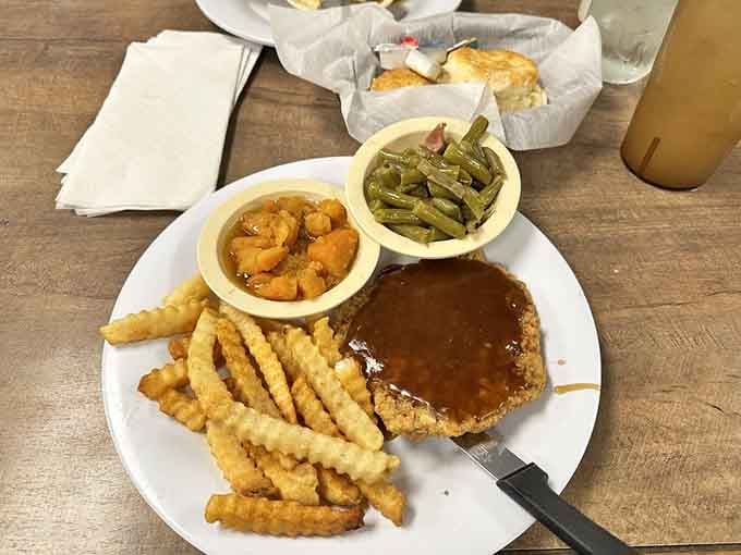 Country fried steak swimming in gravy with crinkle fries and candied yams is pure comfort on a plate.